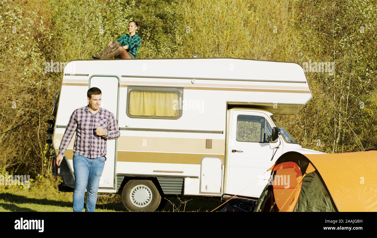 Young girl relaxing on top of retro camper van in mountain wilderness ...