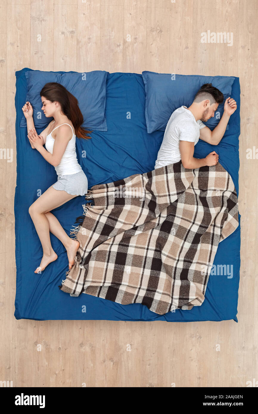 Bedtime. Young couple sleeping on bed on different sides top view Stock ...