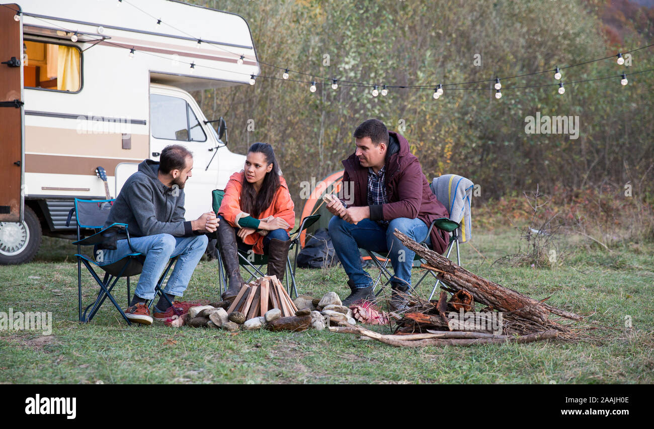 Caucasian friends camping together in mountains with their retro camper ...