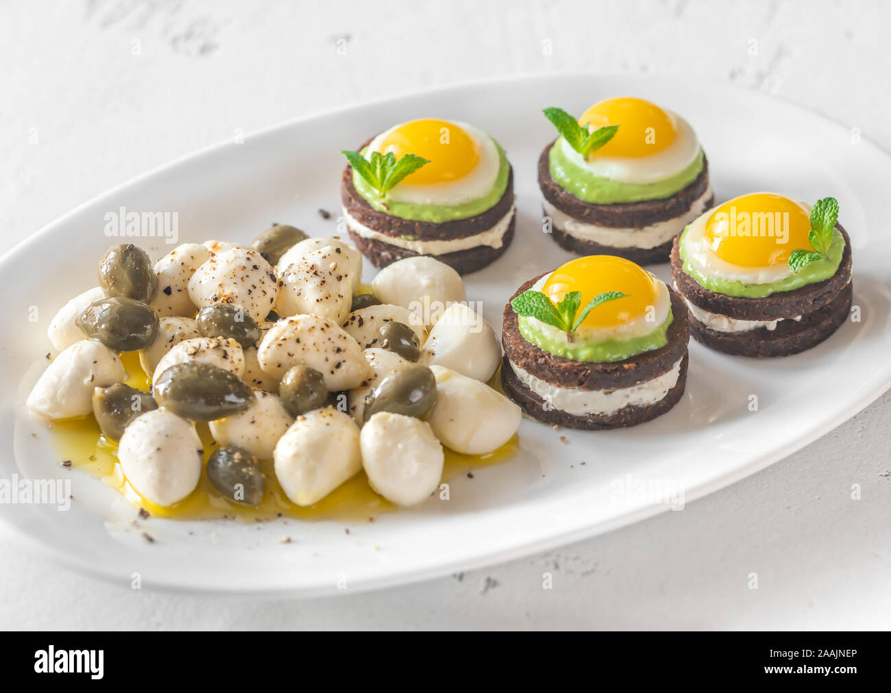 Appetizer with canape, mozzarella and capers on the white plate Stock ...