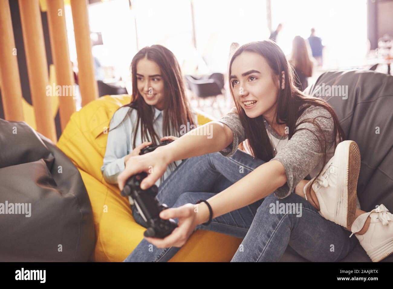 Twin sister sisters play on the console. Girls hold joysticks in their ...