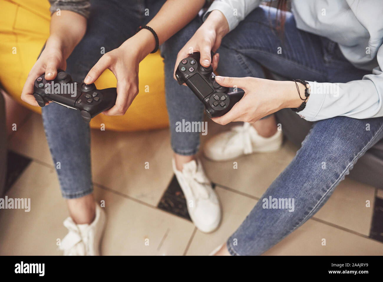 Twin sister sisters play on the console. Girls hold joysticks in their ...