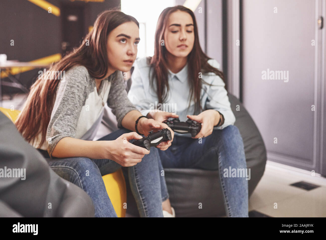 Twin sister sisters play on the console. Girls hold joysticks in their ...