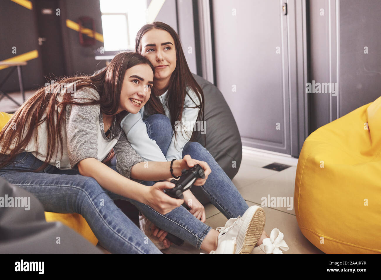 Twin sister sisters play on the console. Girls hold joysticks in their ...
