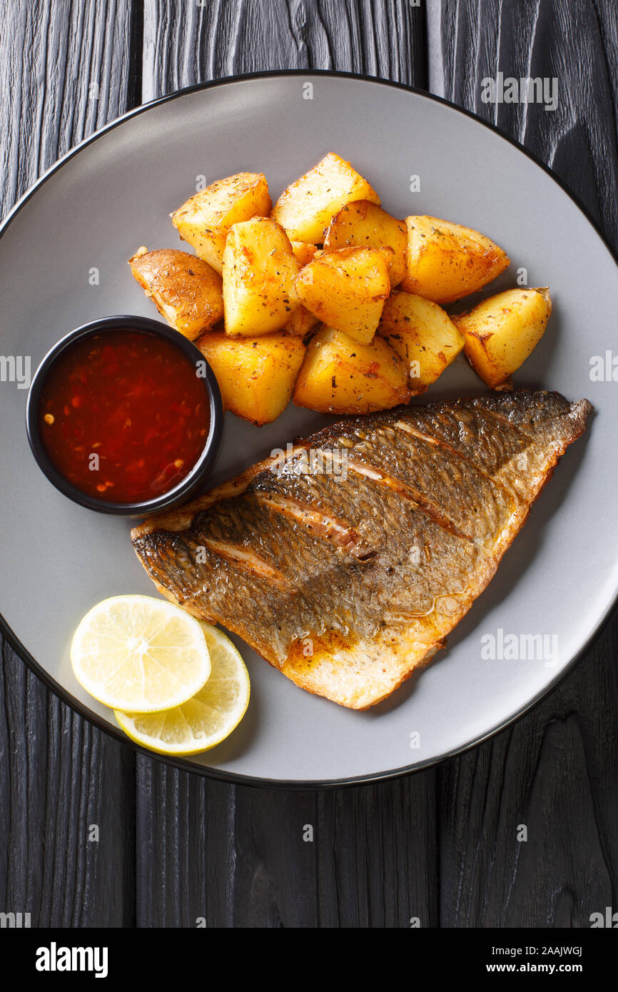 fried dorado fillet with potatoes and sauces close-up on a plate on the ...