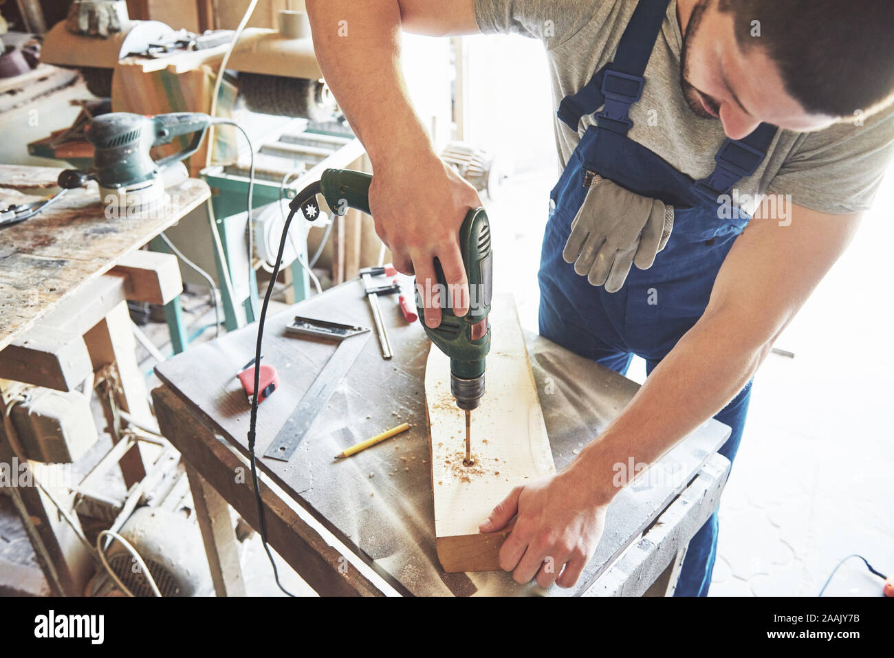 The master works in a studio and drill a hole in a wooden board Stock ...