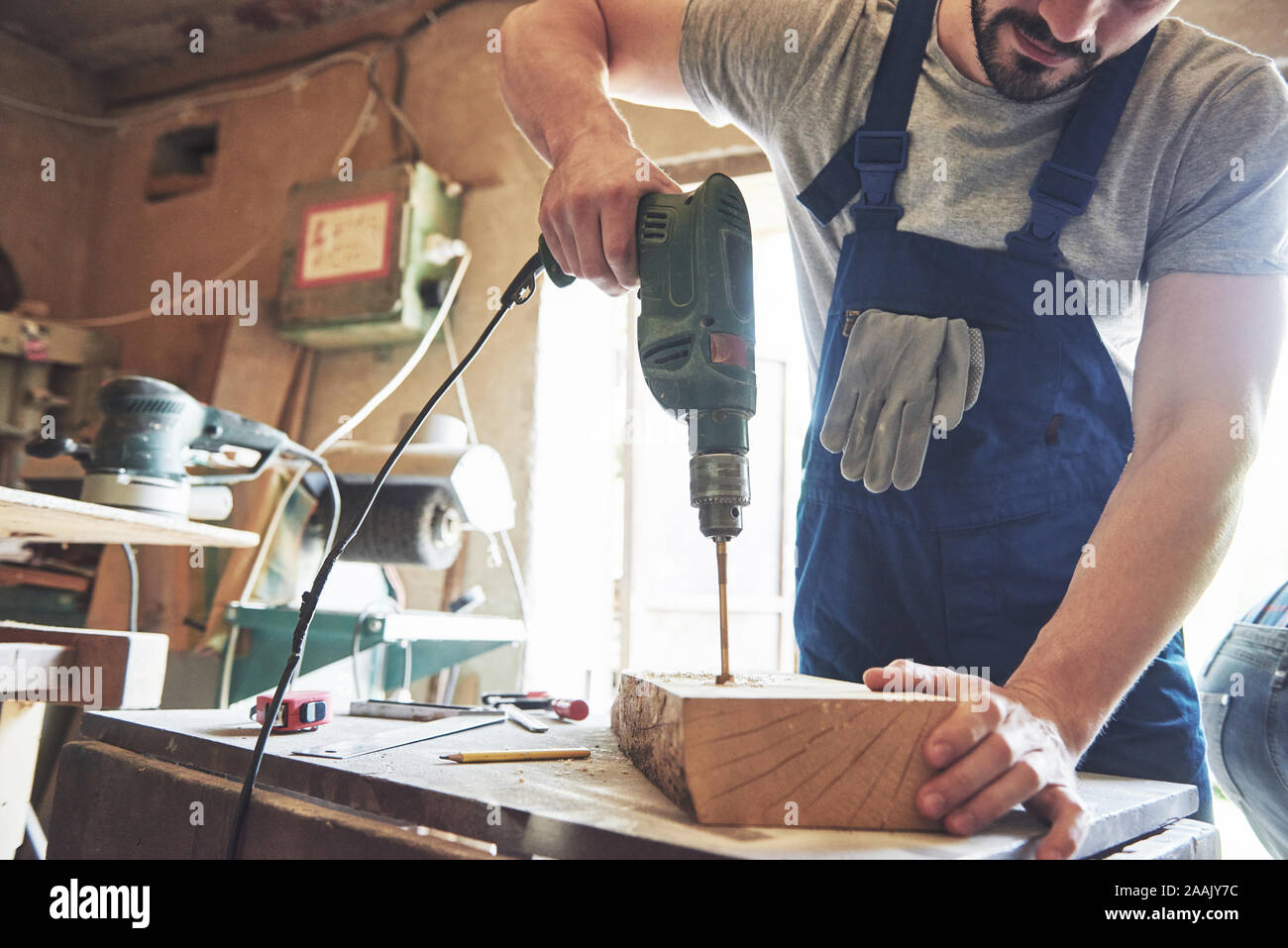 The master works in a studio and drill a hole in a wooden board Stock ...