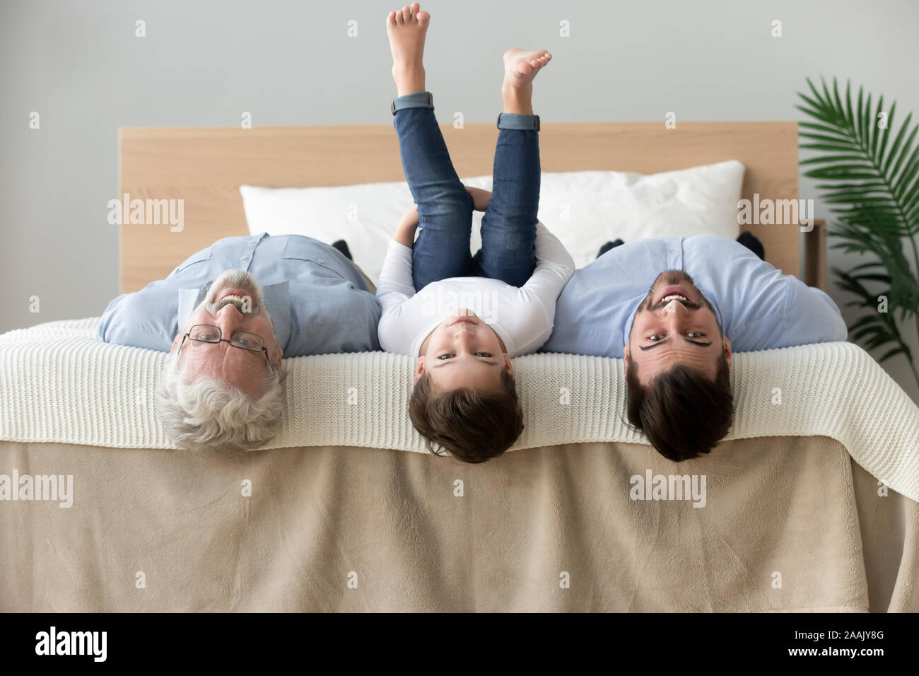 Three generations of men lying on bed together, having fun Stock Photo ...