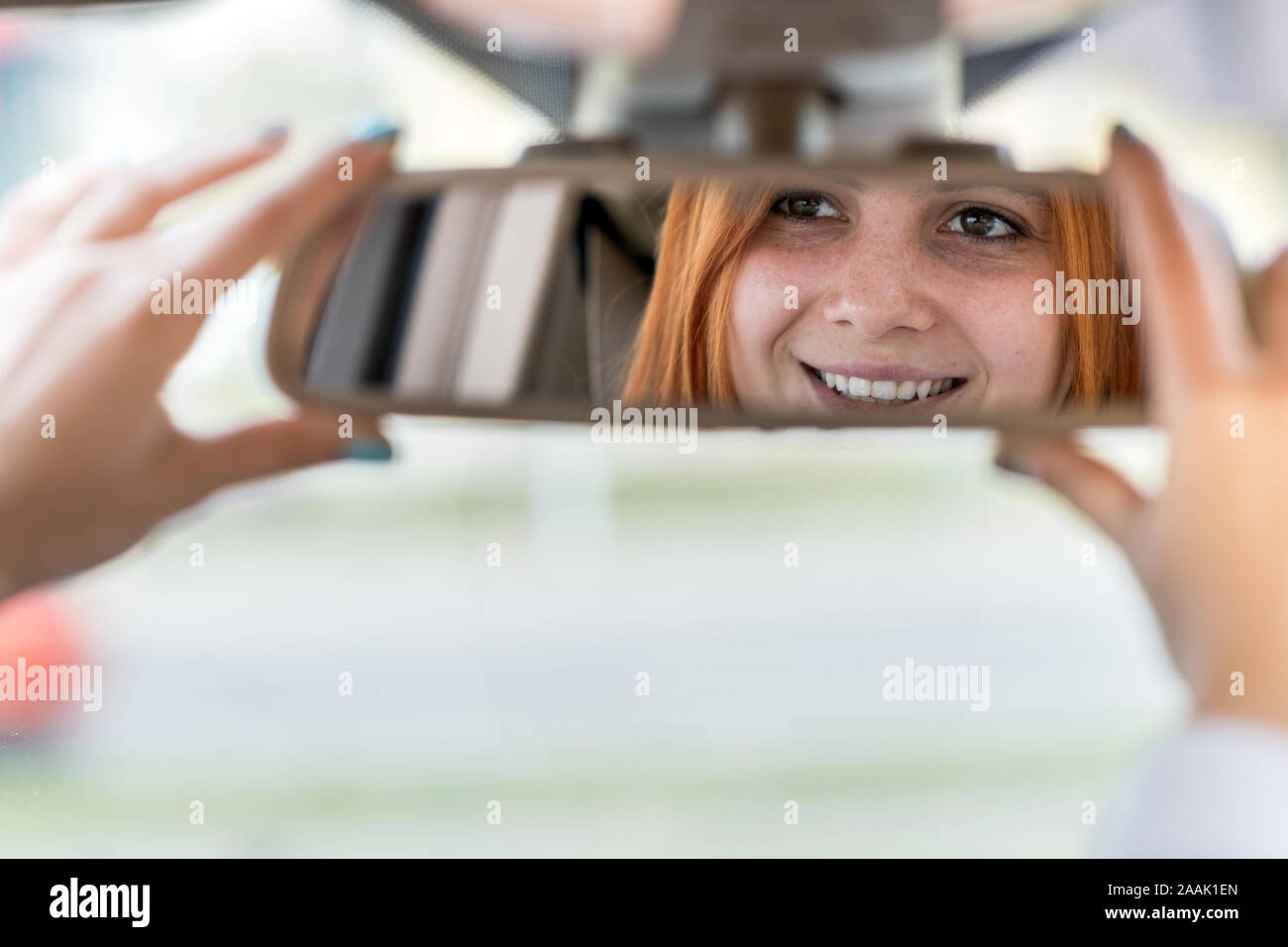Young woman driver checking rear view mirror looking backwards while ...