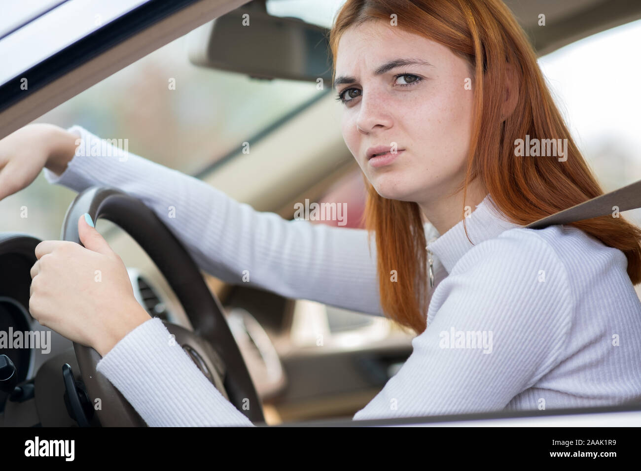 Sad tired yound woman driver sitting behind the car steering wheel in ...
