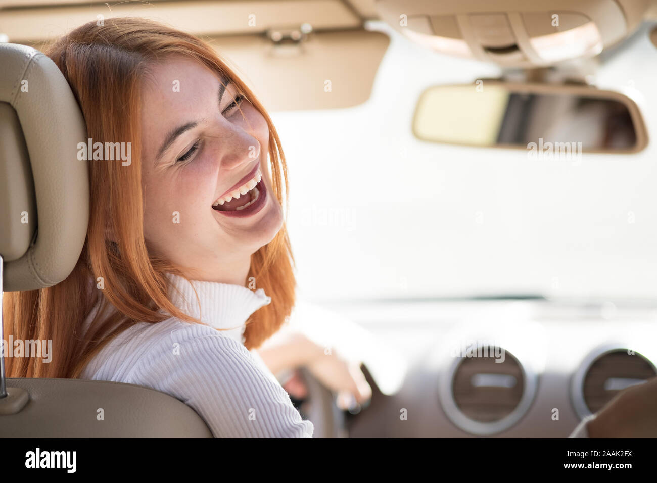 Young redhead woman driver driving a car smiling happily Stock Photo ...