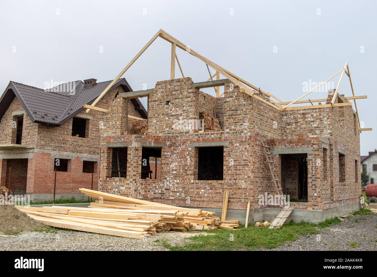 Unfinished brick house with wooden roof structure under construction ...