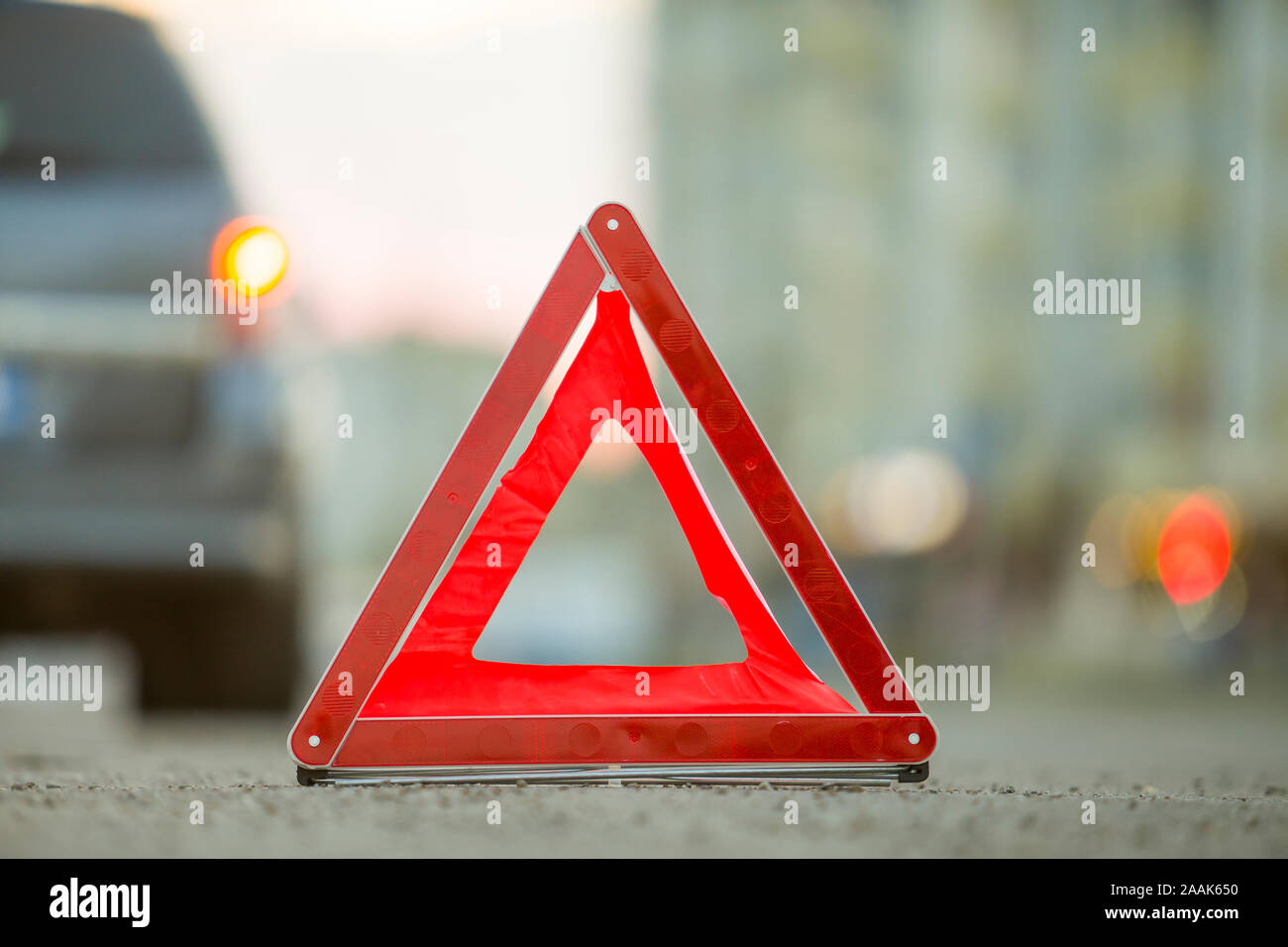 Red emergency triangle stop sign and broken car on a city street Stock ...