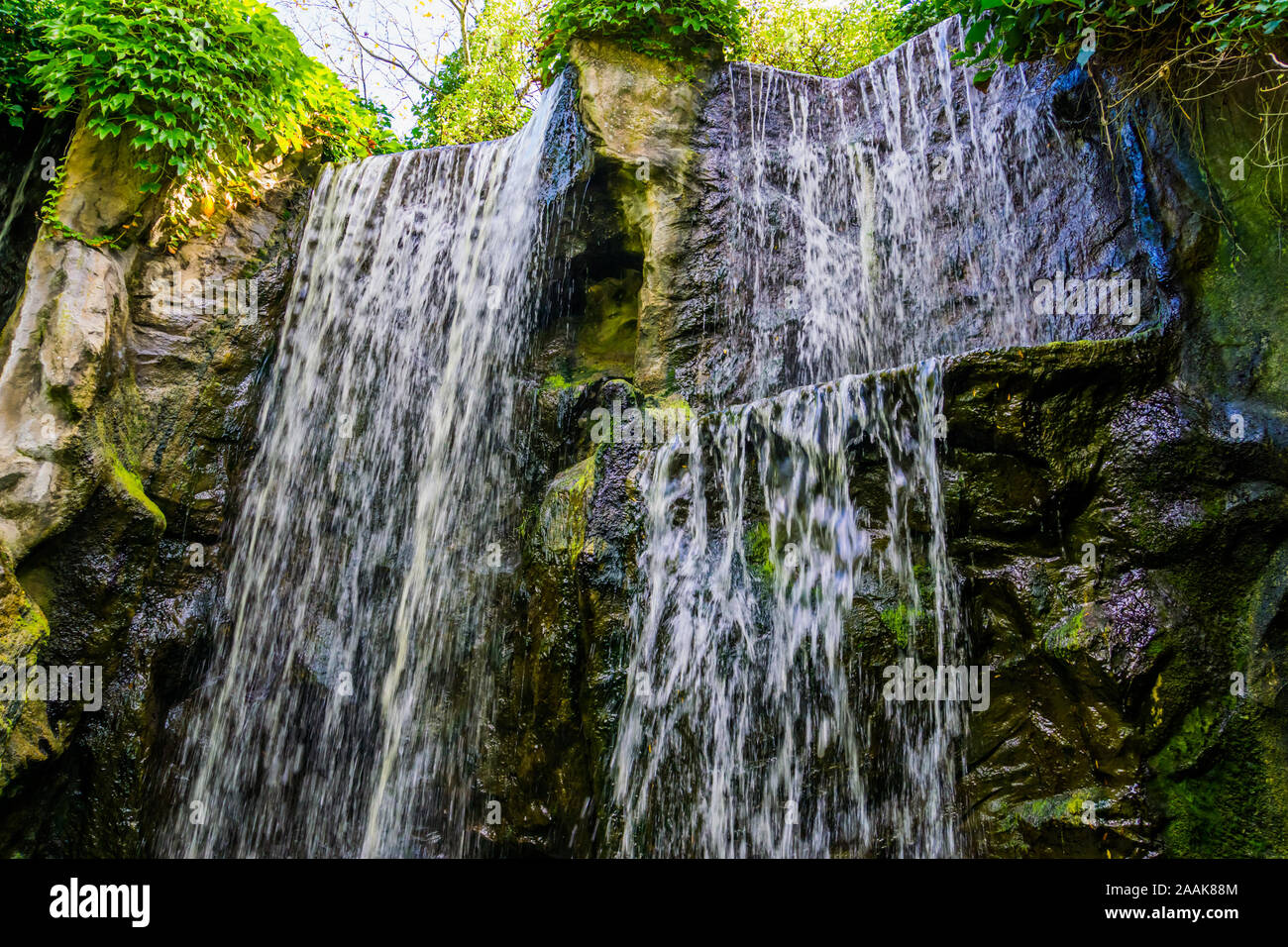 multiple waterfalls streaming of a big rock cliff in a forest, nature ...