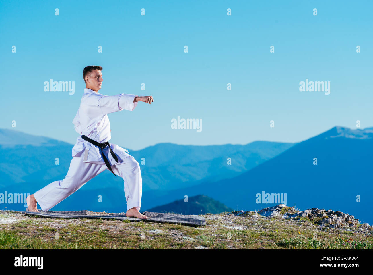 Karate man in a kimono performs a front hand kick (Choku-zuki) while ...