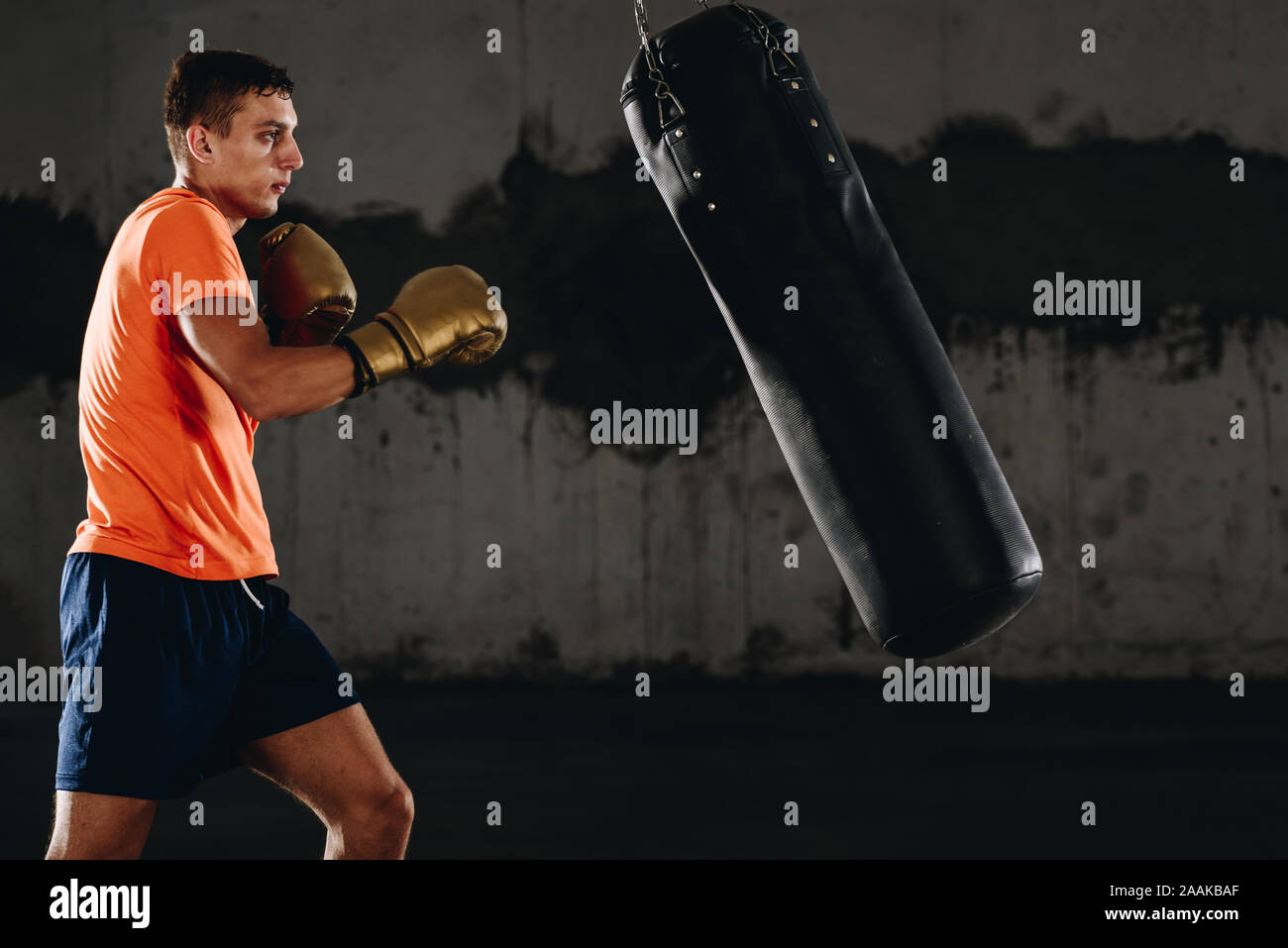 Young man athlete boxing workout in fitness gym on dark background ...