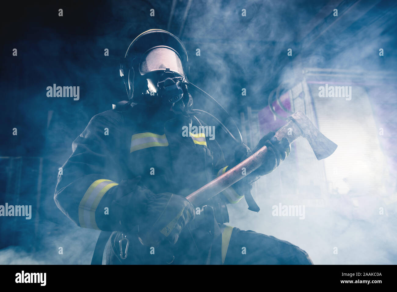 Portrait of a female firefighter while holding an axe and wearing an ...