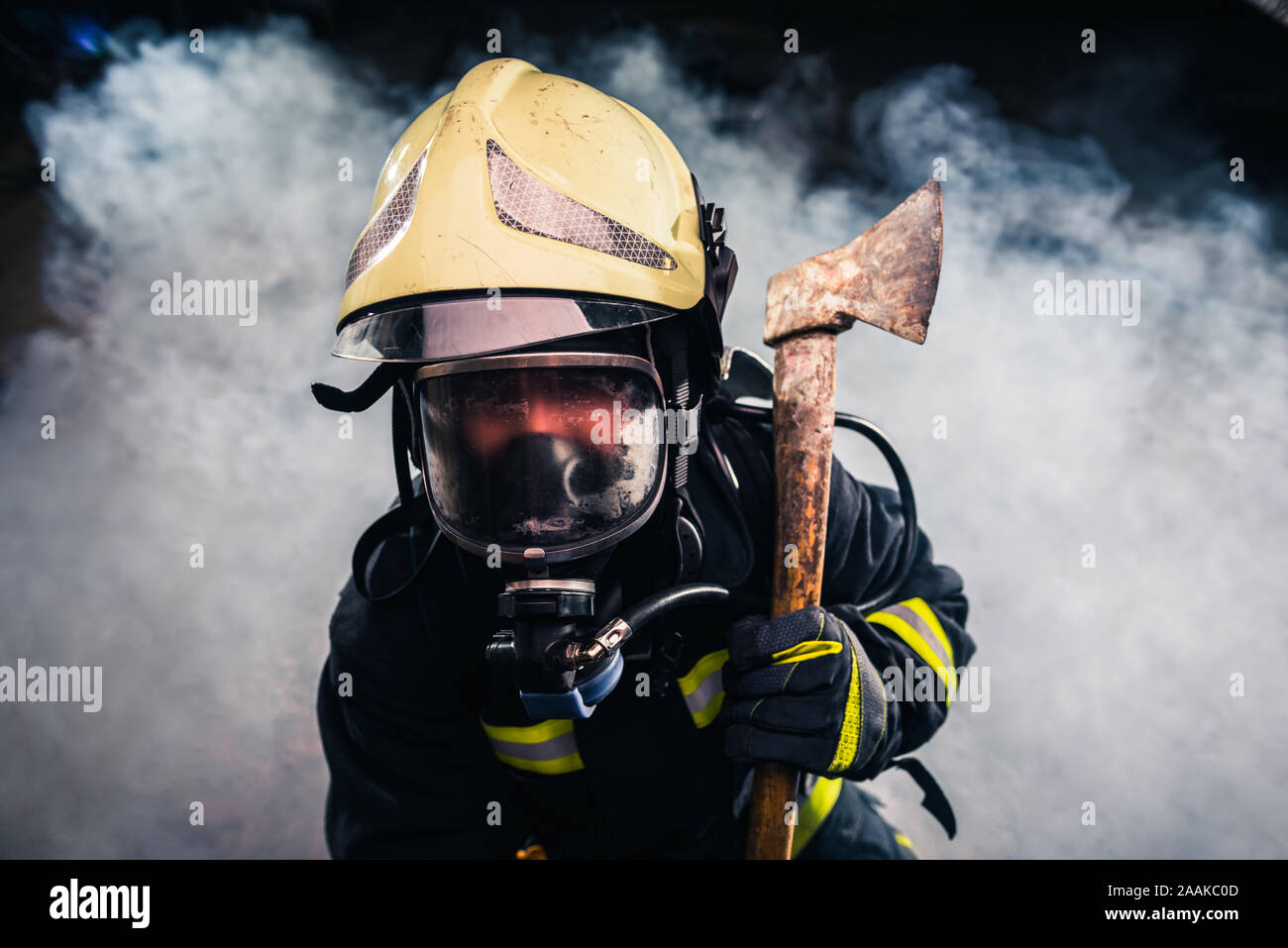 Portrait of a female firefighter while holding an axe and wearing an ...