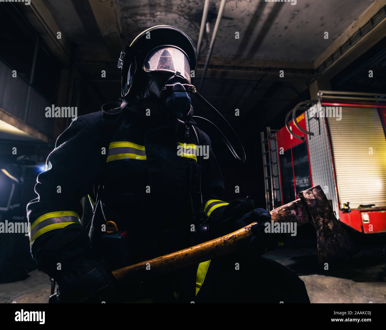 Portrait of a female firefighter while holding an axe and wearing an ...