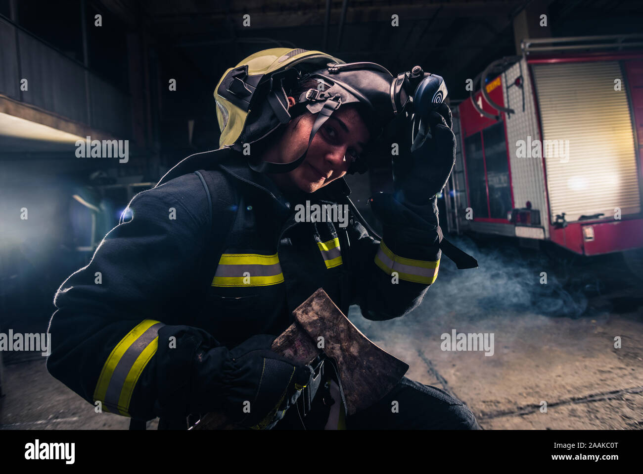 Portrait of a female firefighter while holding an axe and wearing an ...