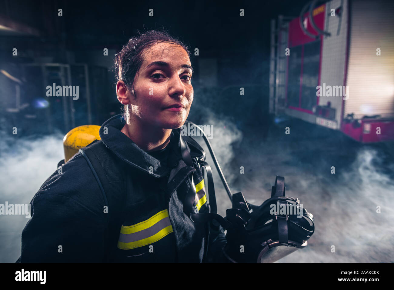 Portrait of a female firefighter while holding an axe and wearing an ...