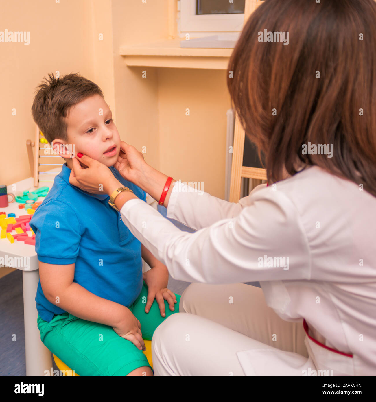 Female Pediatrician check's the throat and mouth of a young cute boy ...