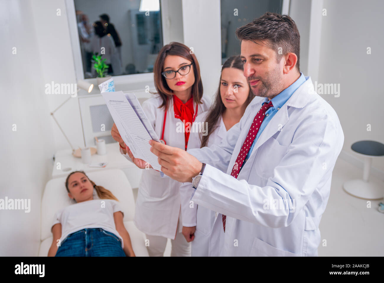 Group of doctors standing next to a sick patient and discussing the ...