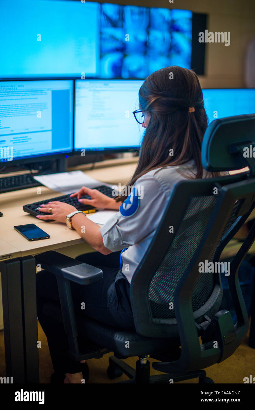 Female security guard sitting back and monitoring modern CCTV cameras ...