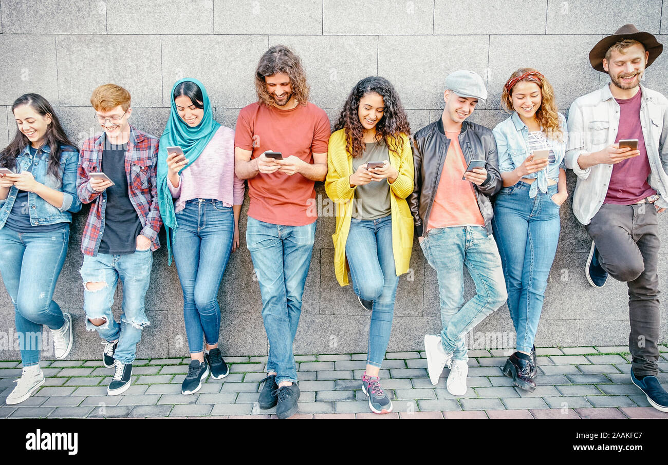 Group of fashion friends watching on their smart mobile phones ...