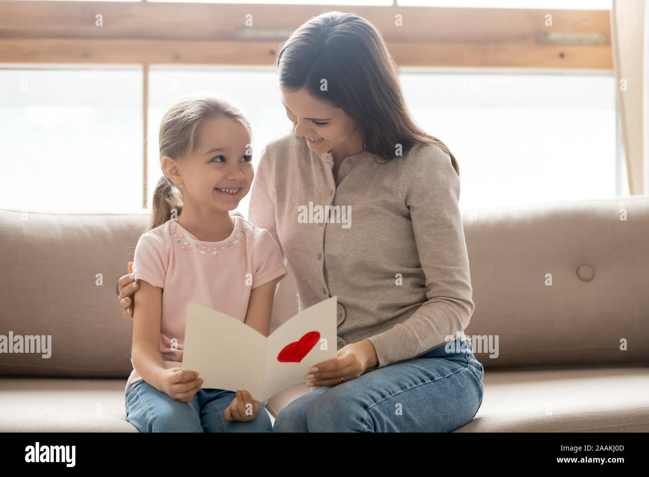 Cute little daughter congratulate mom presenting greeting card Stock ...