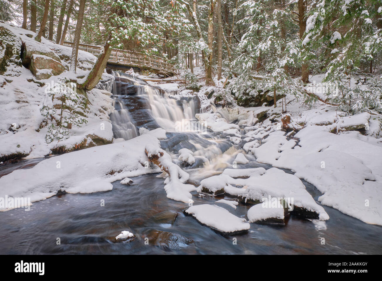 After the first snowfall of the season, water runs under a footbridge ...