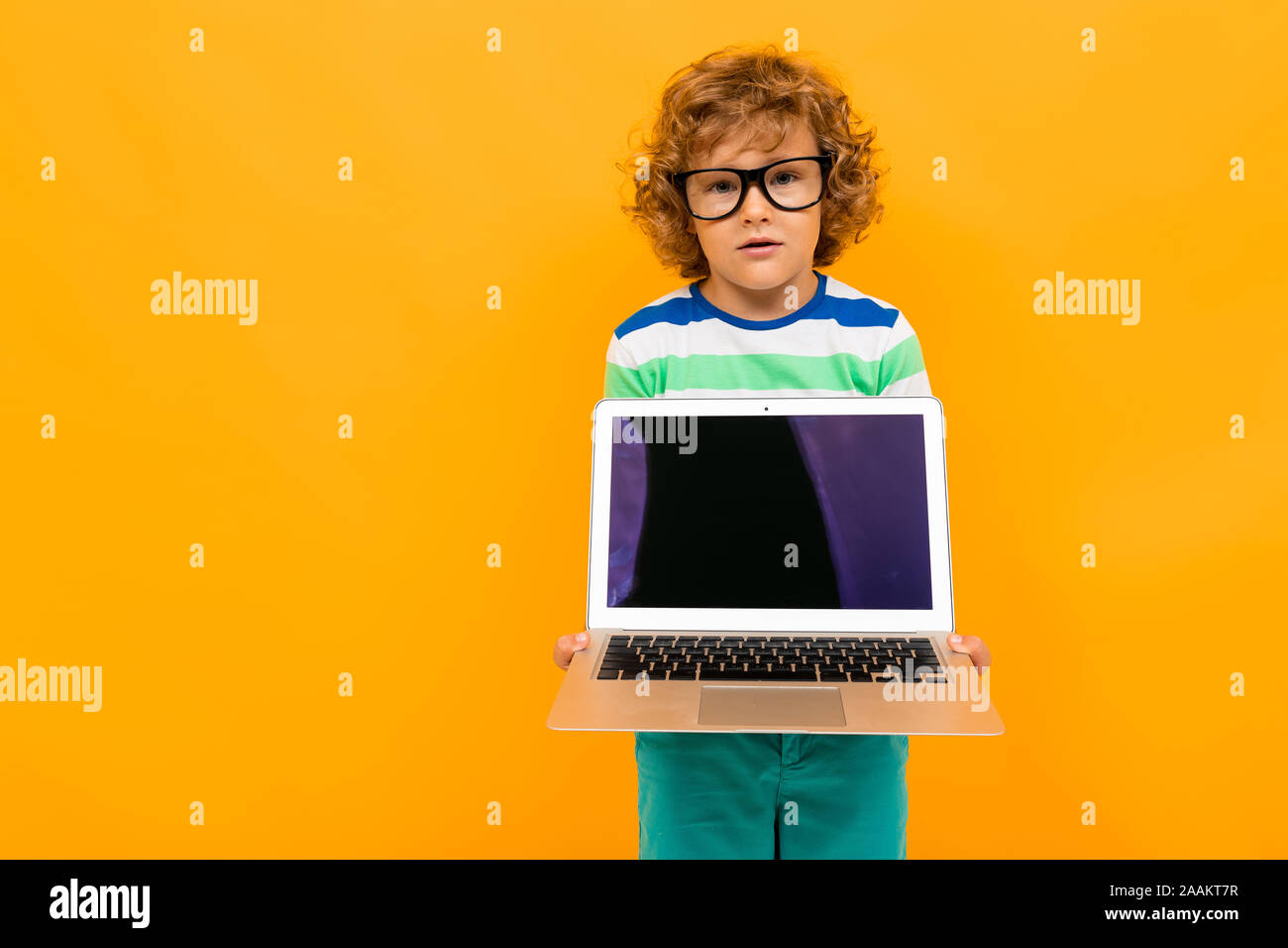 smart schoolboy with a laptop on a yellow background Stock Photo - Alamy