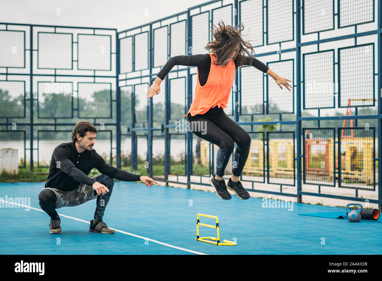 Hurdle jumping training outdoors. Sporty woman jumping over the hurdle ...