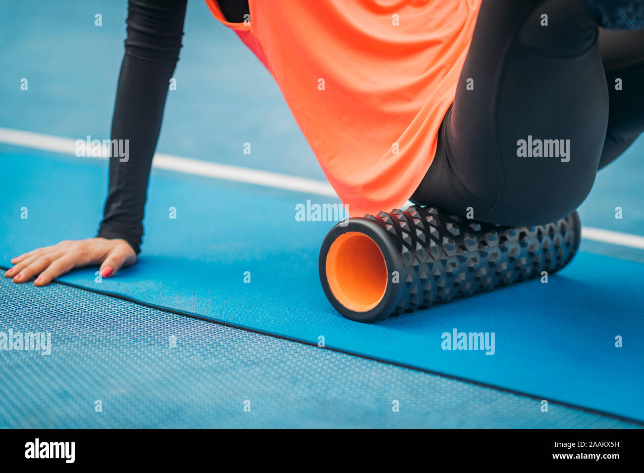 Close-up image of female athlete, stretching with foam roller, outdoors ...