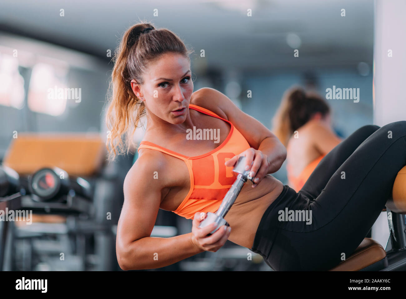 Female athlete doing highly effective sit-ups with dumbbell in modern ...