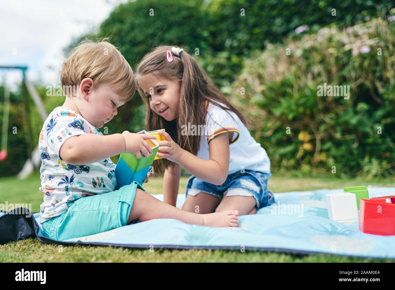 Sisters playing with blocks on picnic blanket Stock Photo - Alamy