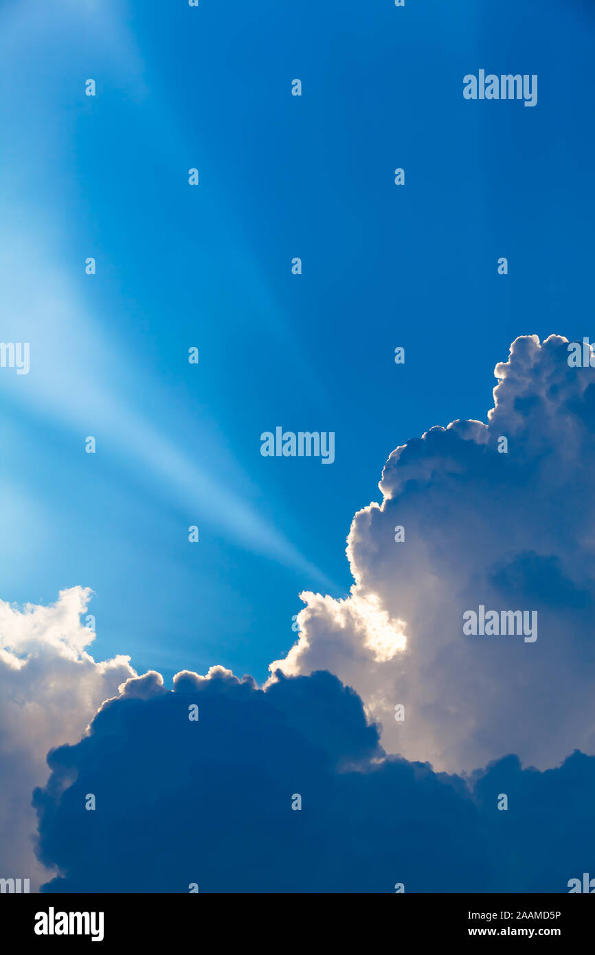 Small ray of sunlight up to blue sky behind dark clouds (copy space ...