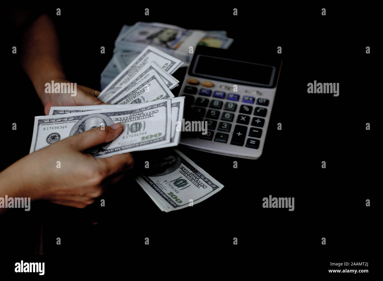 Businessmen women counting money on a stack of 100 US dollars banknotes ...