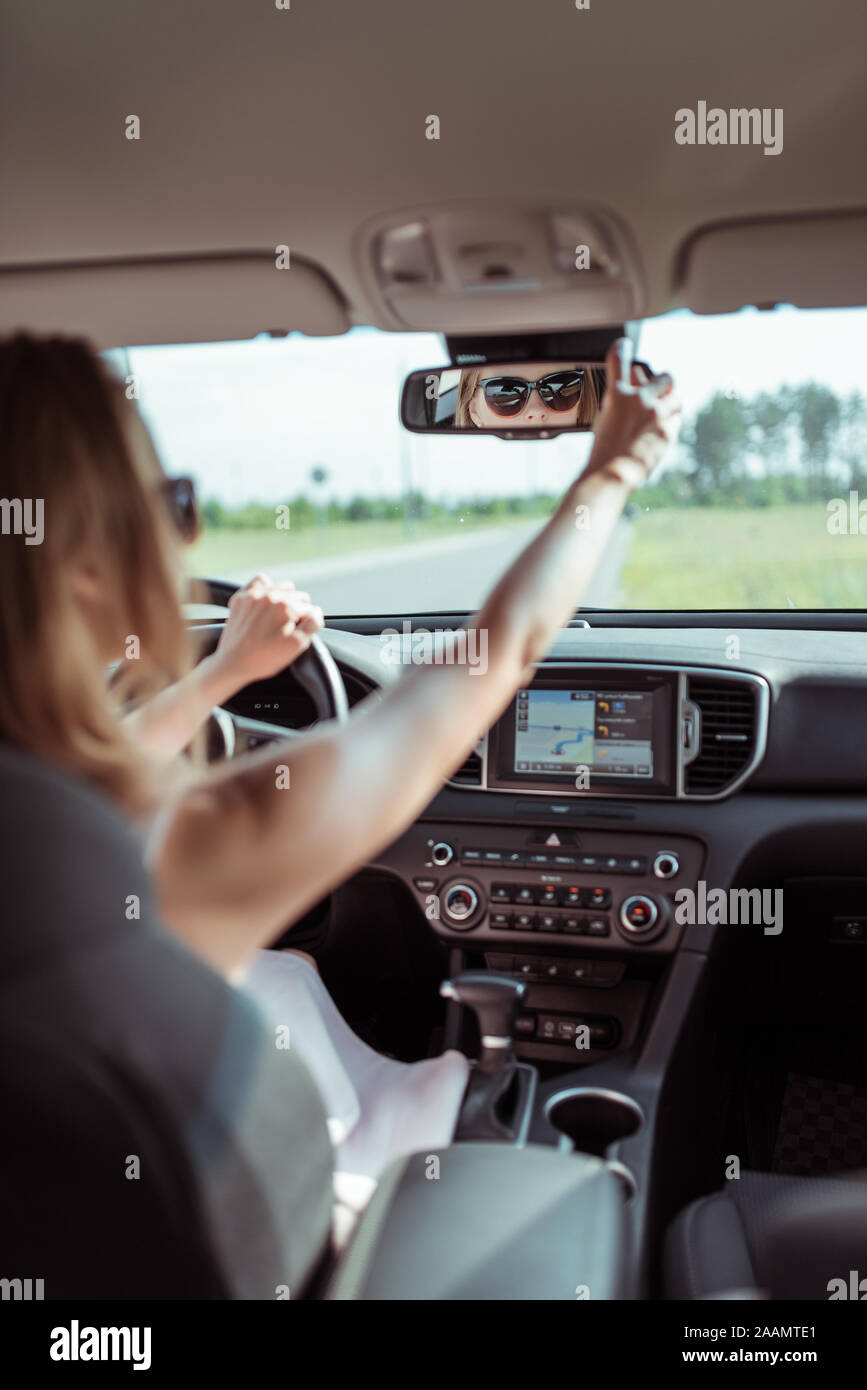 woman in car, adjusts and rearview mirror, driving safety in car ...