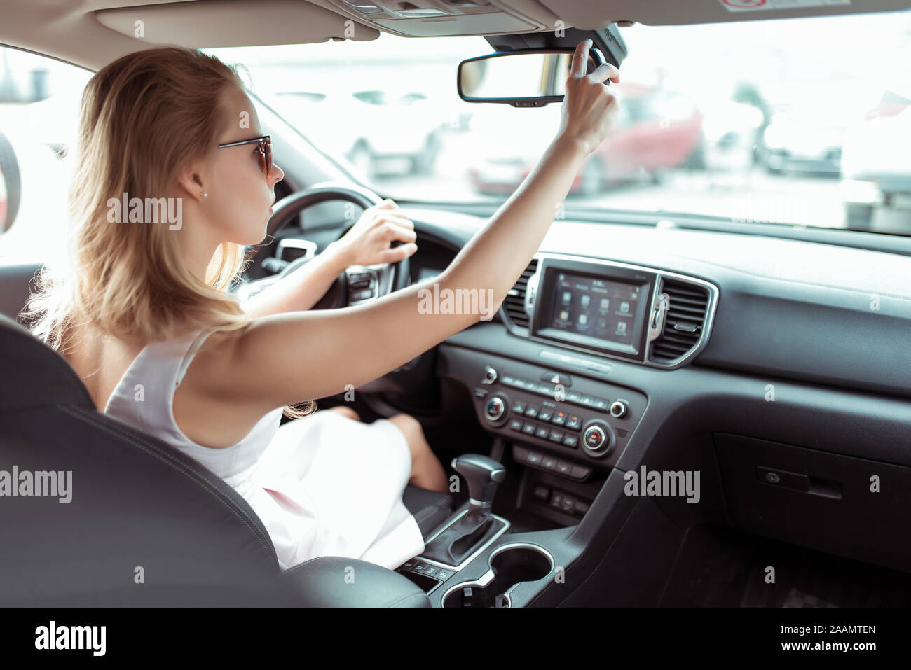 Woman In Car Adjusts And Rearview Mirror Driving Safety In Car Parking And Rear Traffic woman-in-car-adjusts-and-rearview-mirror-driving-safety-in-car-parking-and-rear-traffic