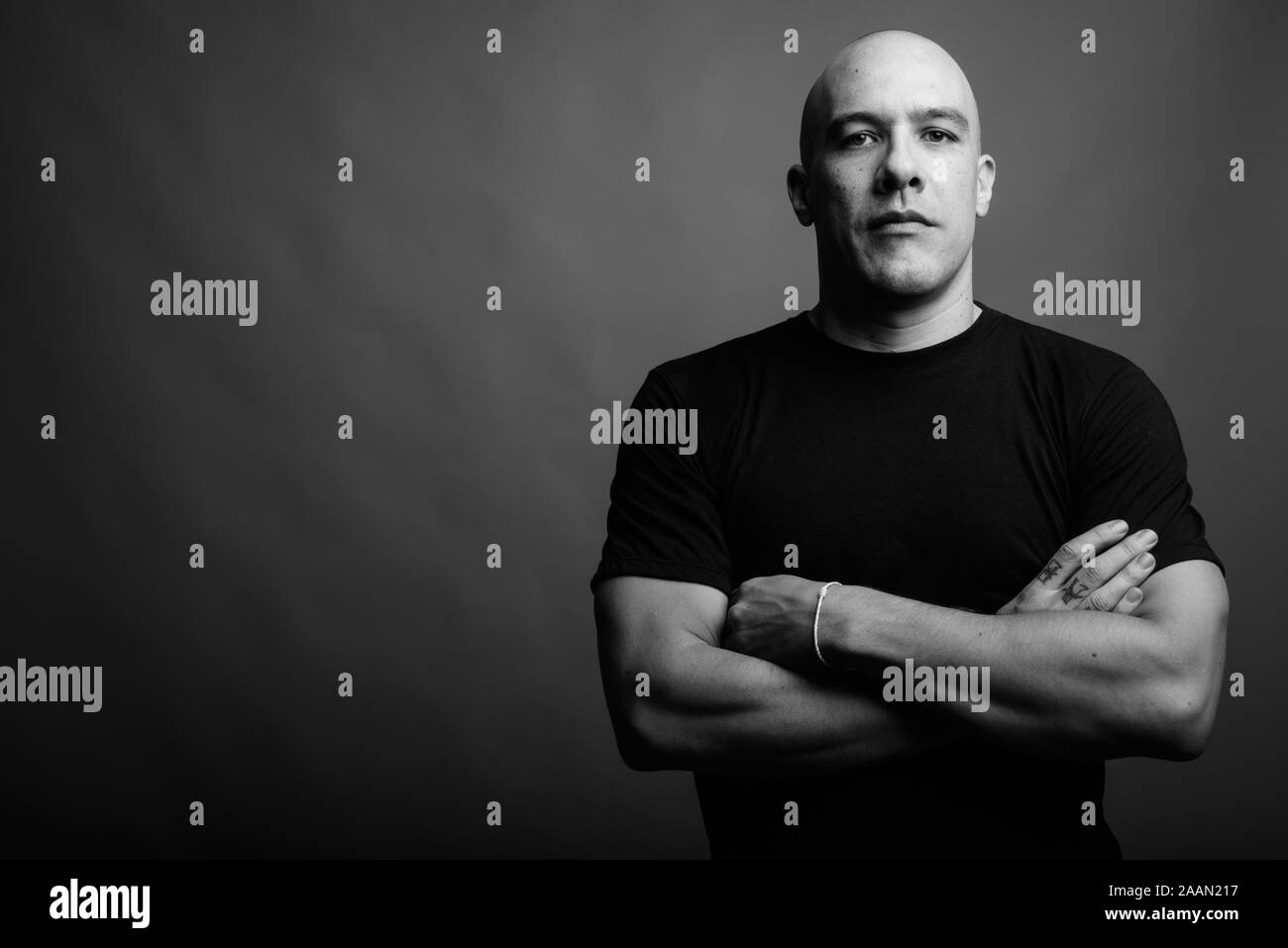 Handsome bald man against gray background in black and white Stock ...