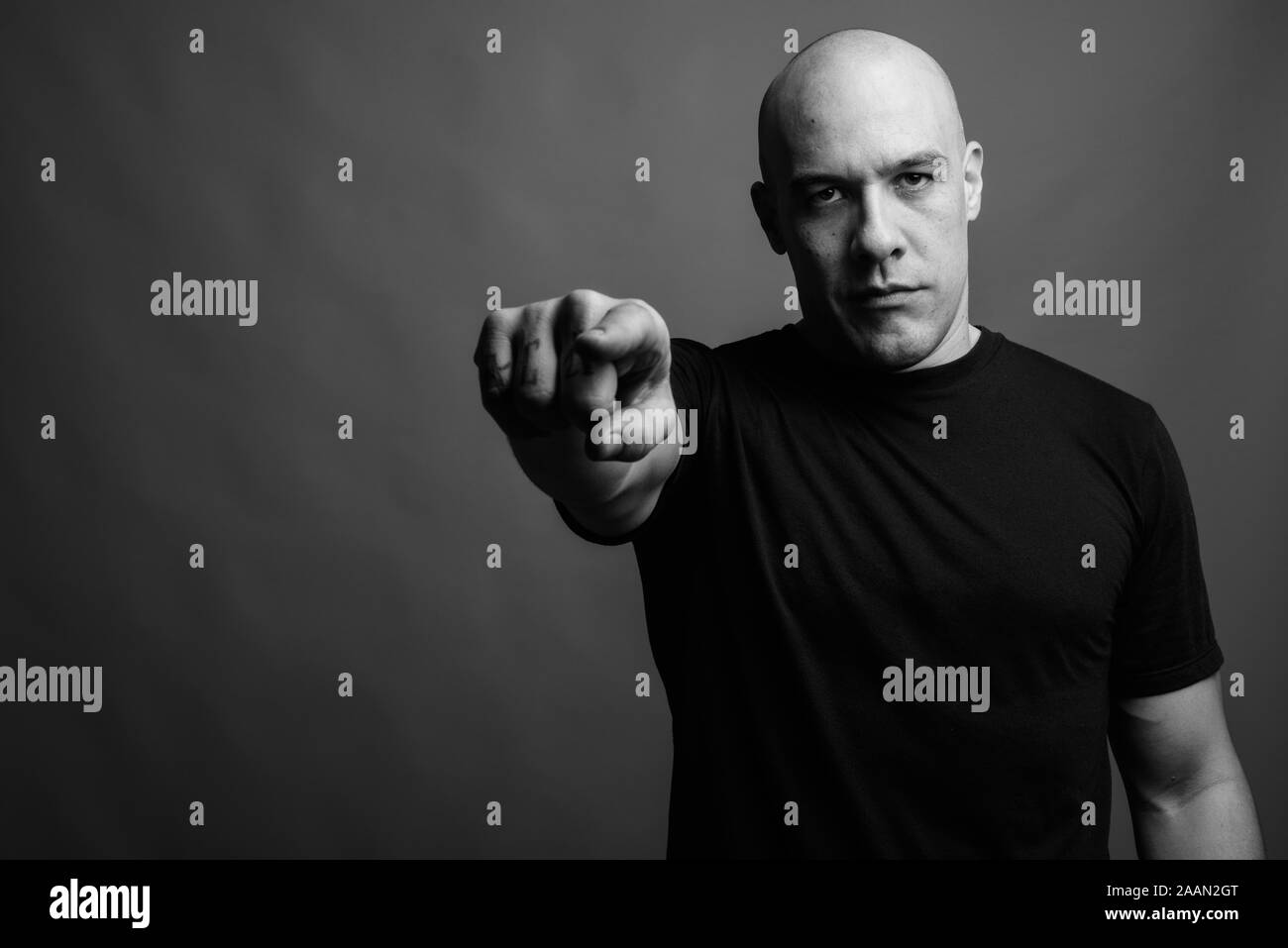 Handsome bald man against gray background in black and white Stock ...