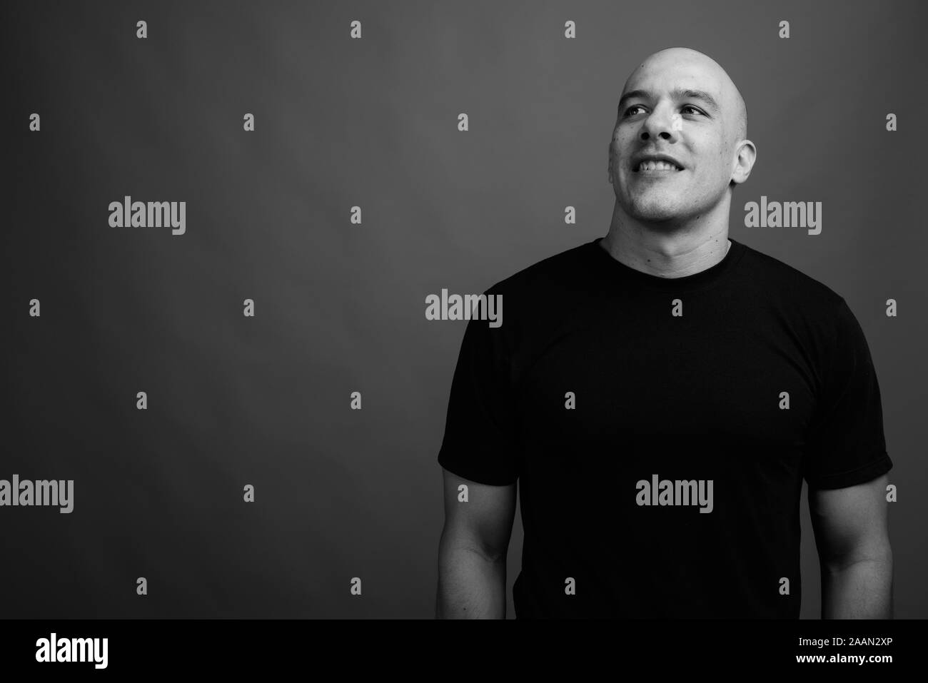 Handsome bald man against gray background in black and white Stock ...