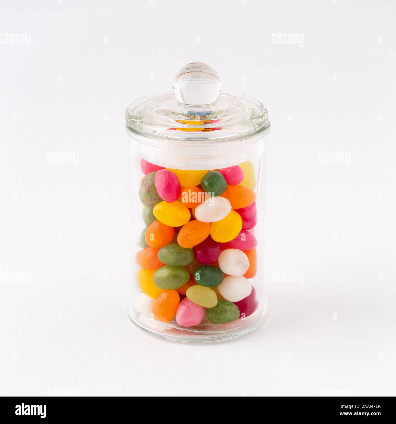 glass jar filled with candy and caramel with the lid closed on white ...