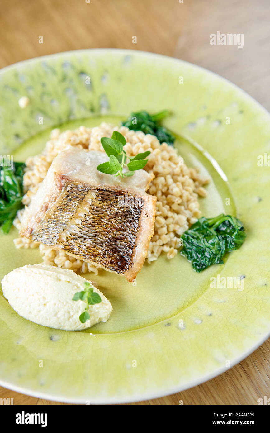 Roasted pike perch or cod fish with bulgur. Dish decorated with a ...