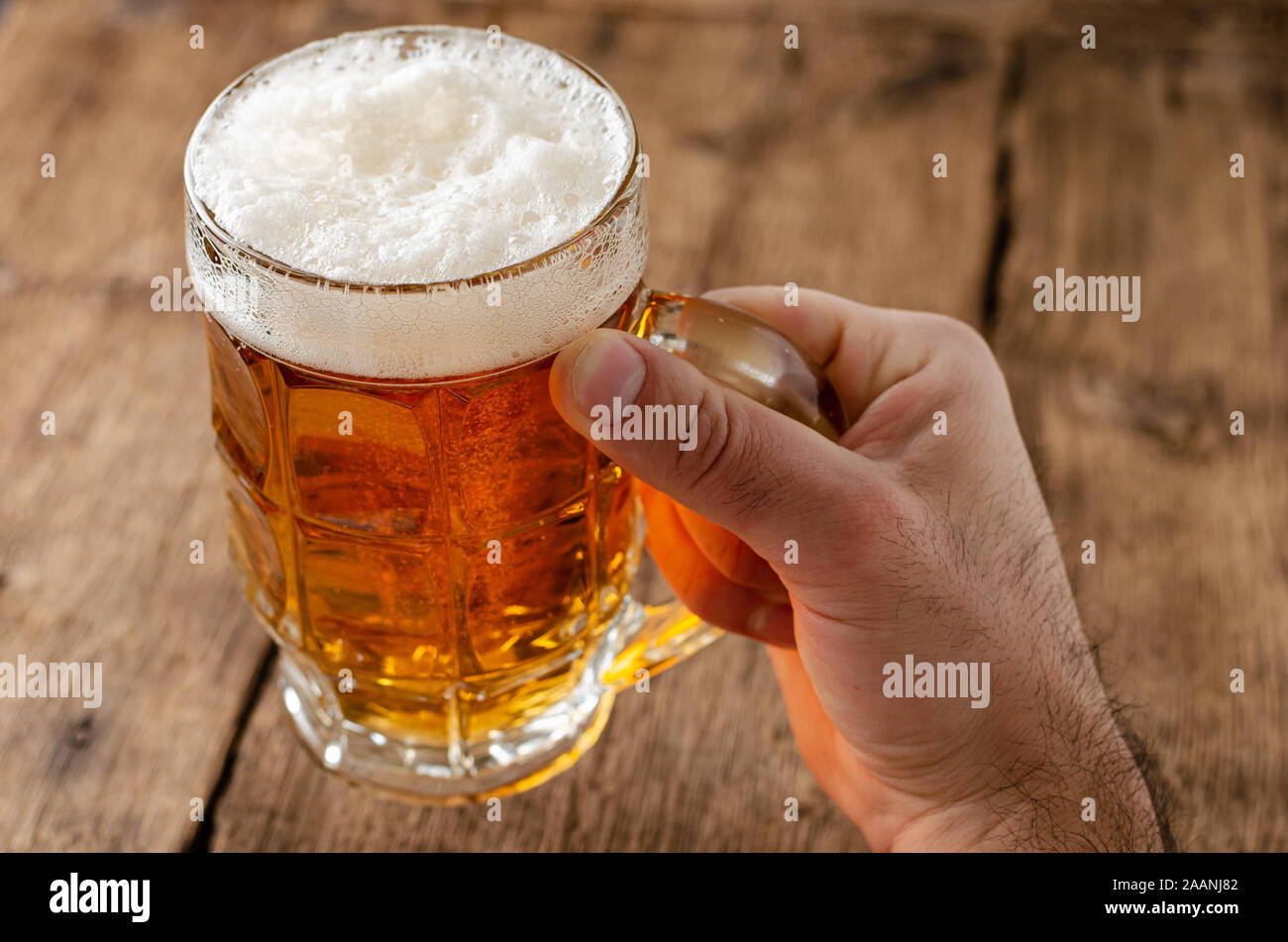 Hand holding a glass of lager beer on wooden rustic background Stock ...