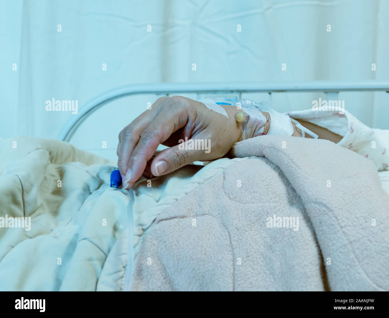 Hand with saline IV drip needle on hospital bed Stock Photo - Alamy
