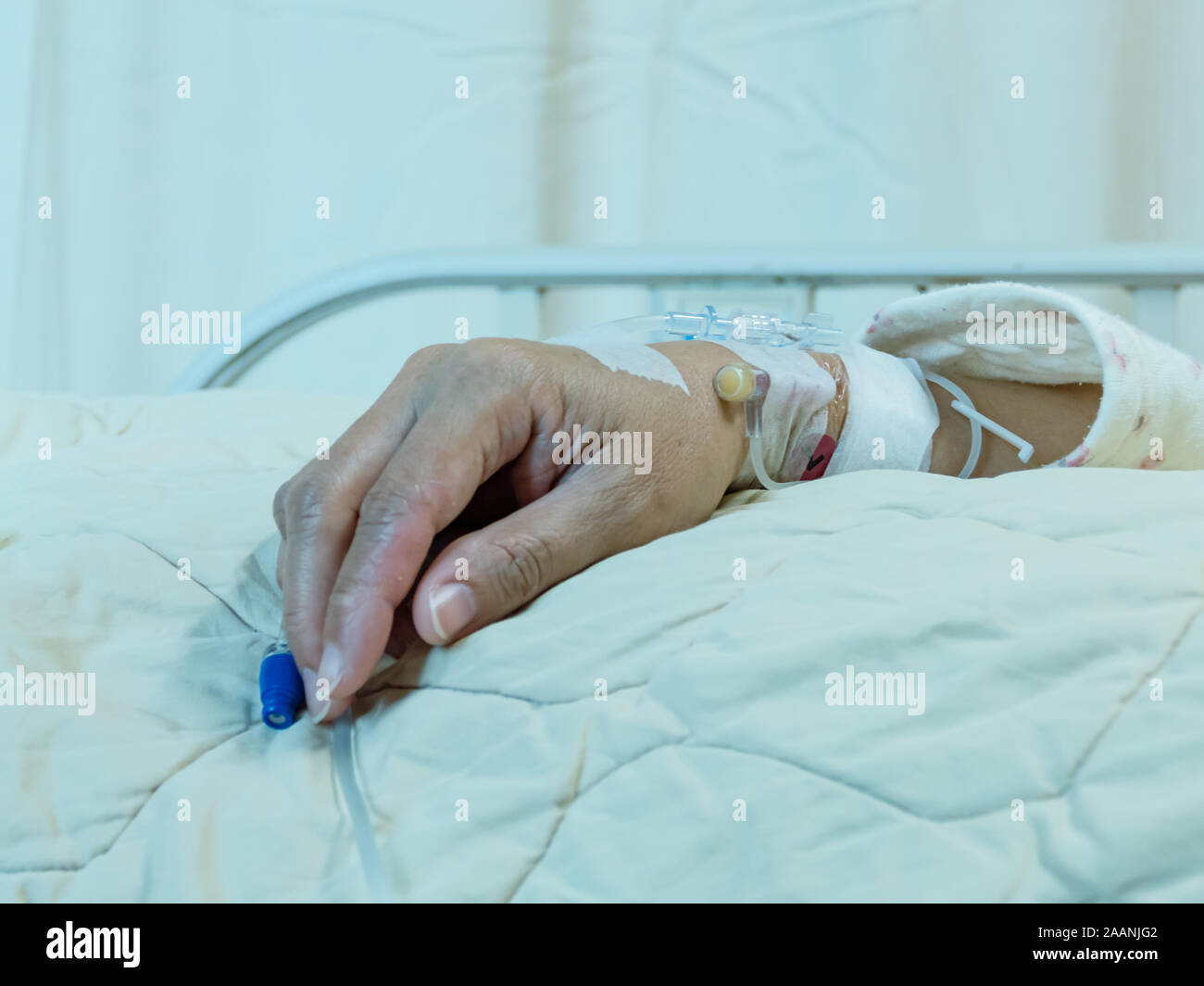 Hand with saline IV drip needle on hospital bed Stock Photo - Alamy