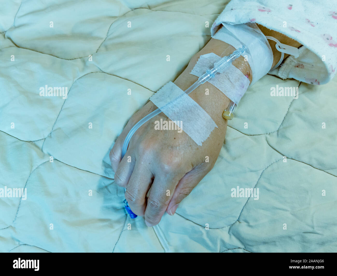 Hand with saline IV drip needle on hospital bed Stock Photo - Alamy