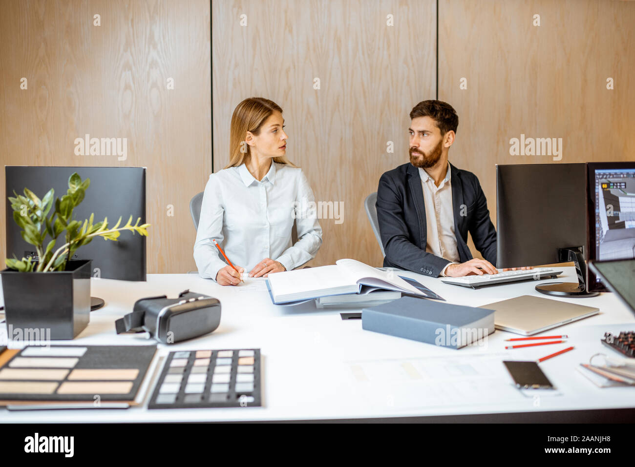 Two office employees making some creative work while sitting together ...